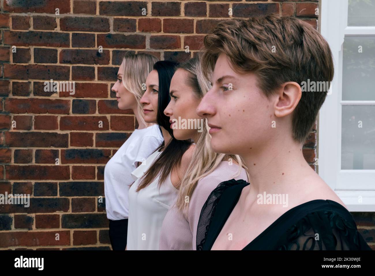 Non-binary person with friends standing side by side in front of wall ...