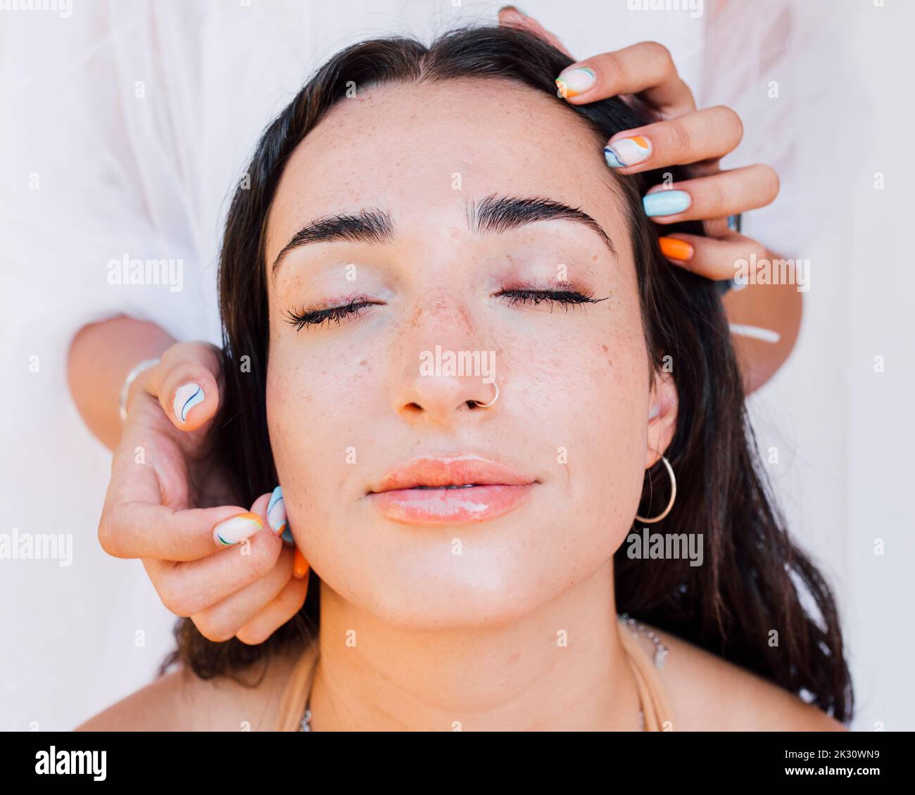 Hands touching face of young woman with eyes closed Stock Photo - Alamy
