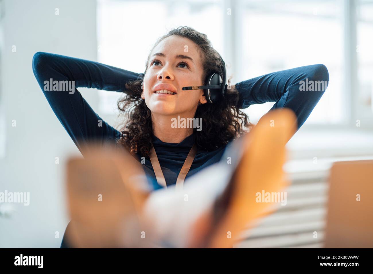 Thoughtful customer service representative with hands behind head ...