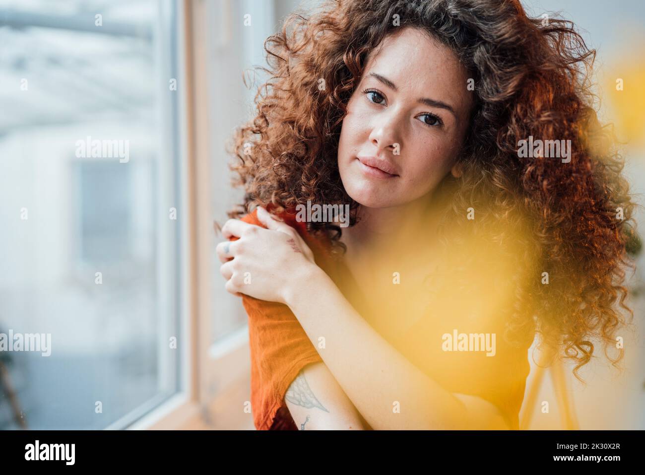 Beautiful woman with curly hair by window at home Stock Photo - Alamy