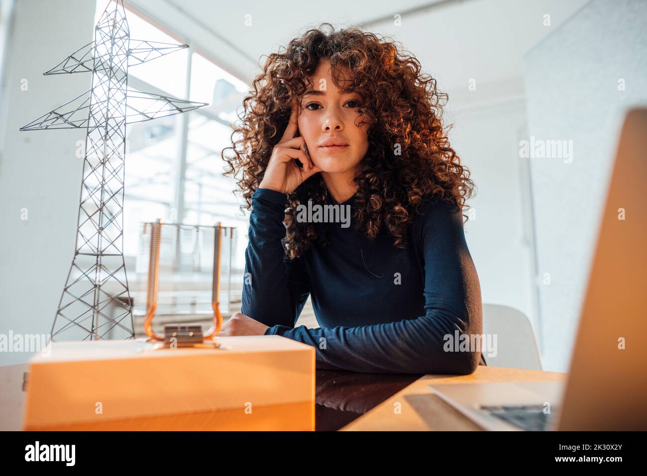 Businesswoman with semiconductor and electricity pylon model at desk in ...