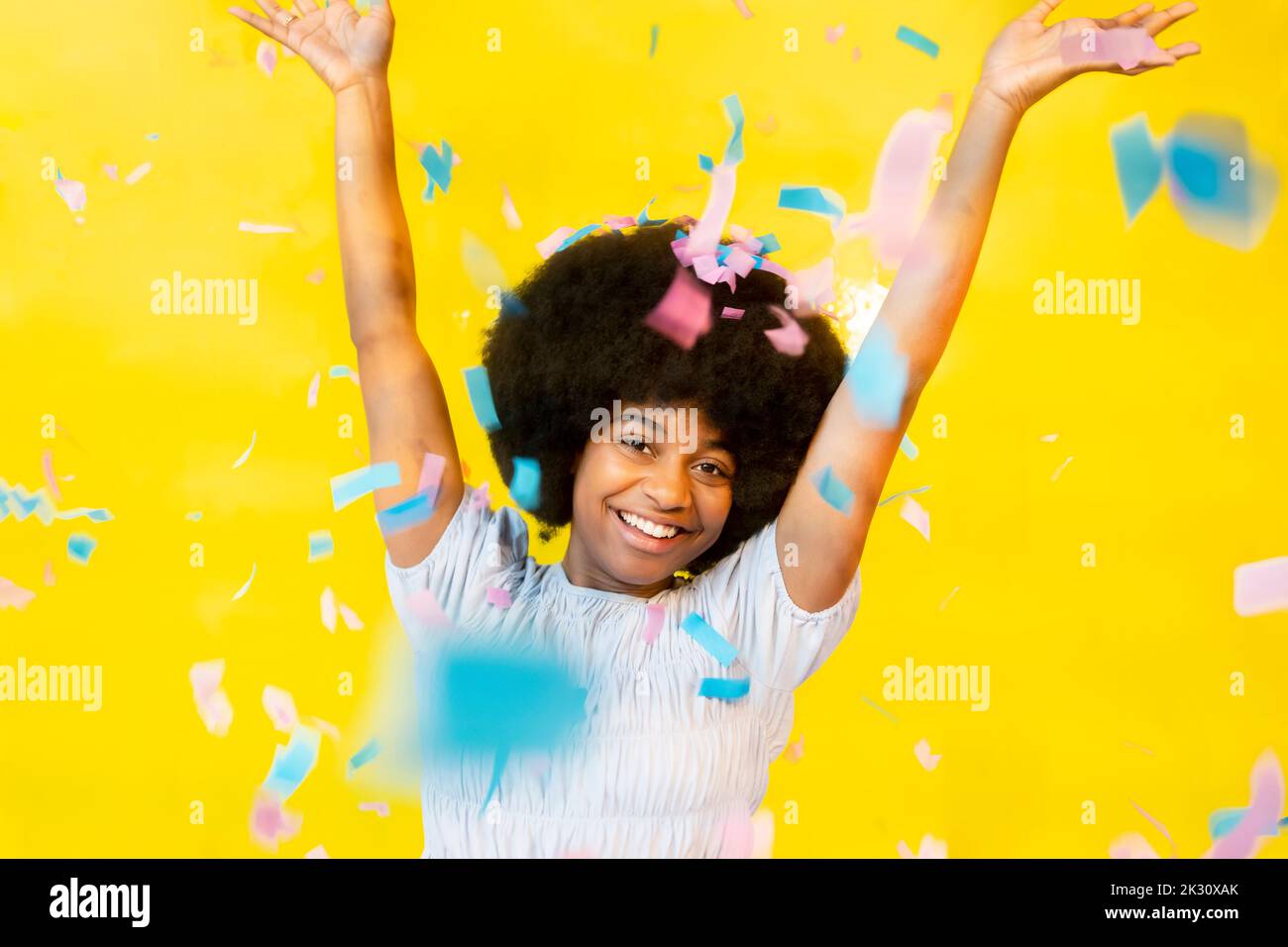 Happy young woman throwing confetti against yellow background Stock ...