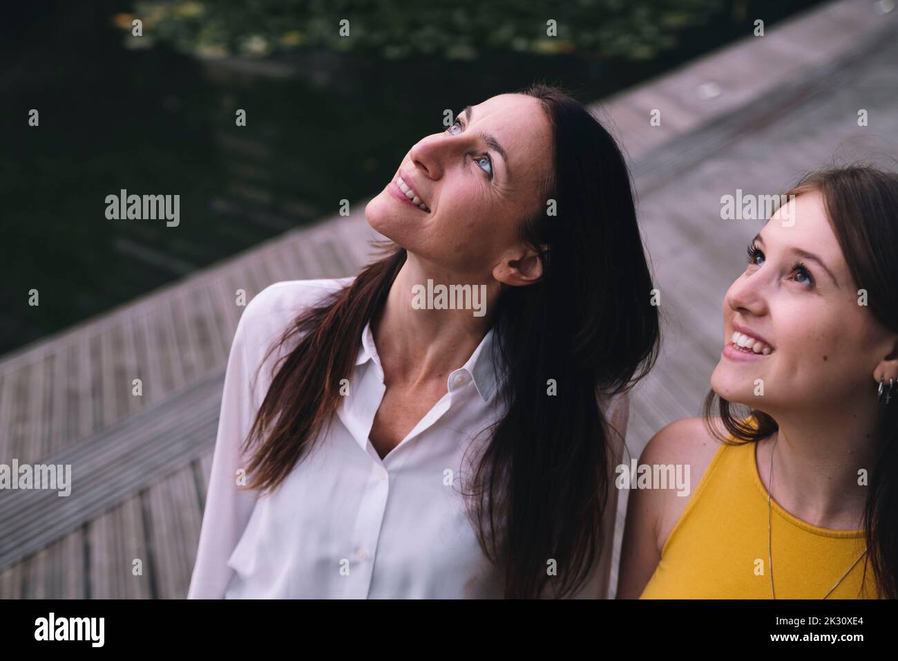 Two women looking up and smiling at footpath Stock Photo - Alamy