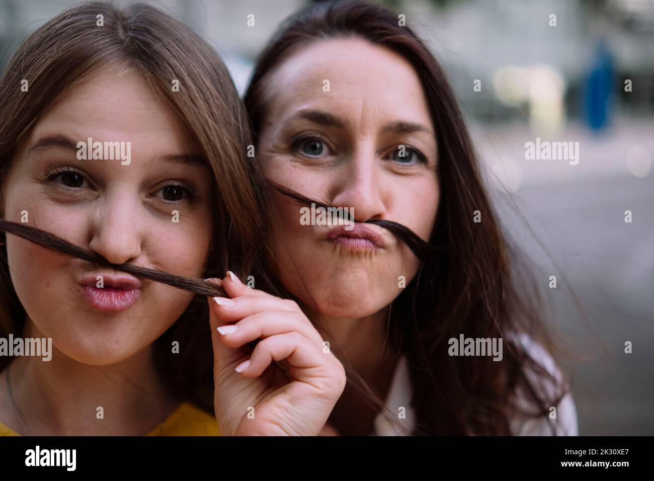 Two women having fun making mustache with hair Stock Photo - Alamy