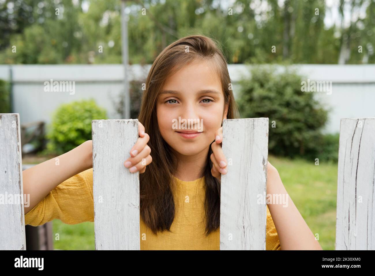 Smiling girl standing behind fence at back yard Stock Photo - Alamy