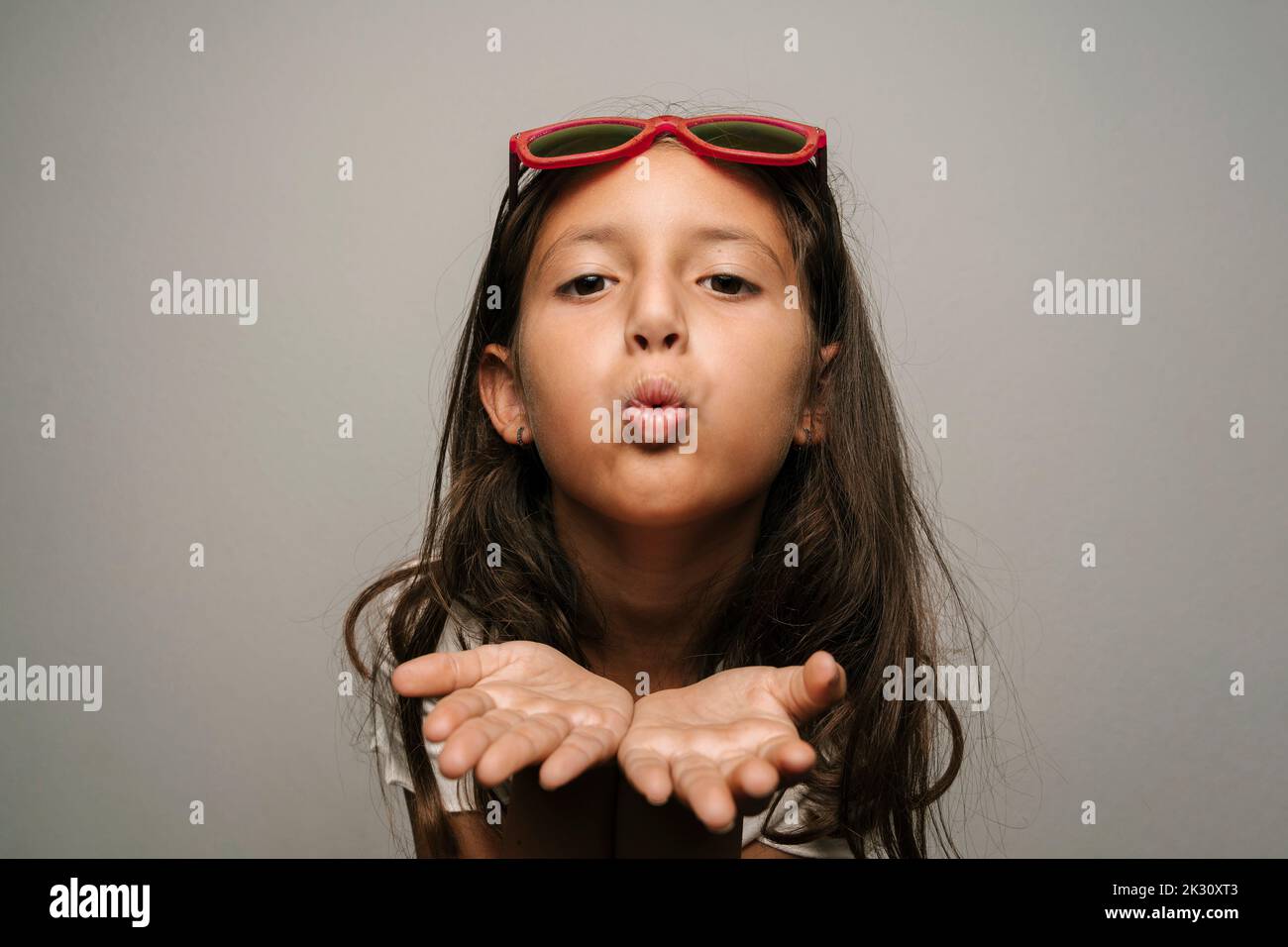 Cute girl with sunglasses blowing kiss against gray background Stock ...
