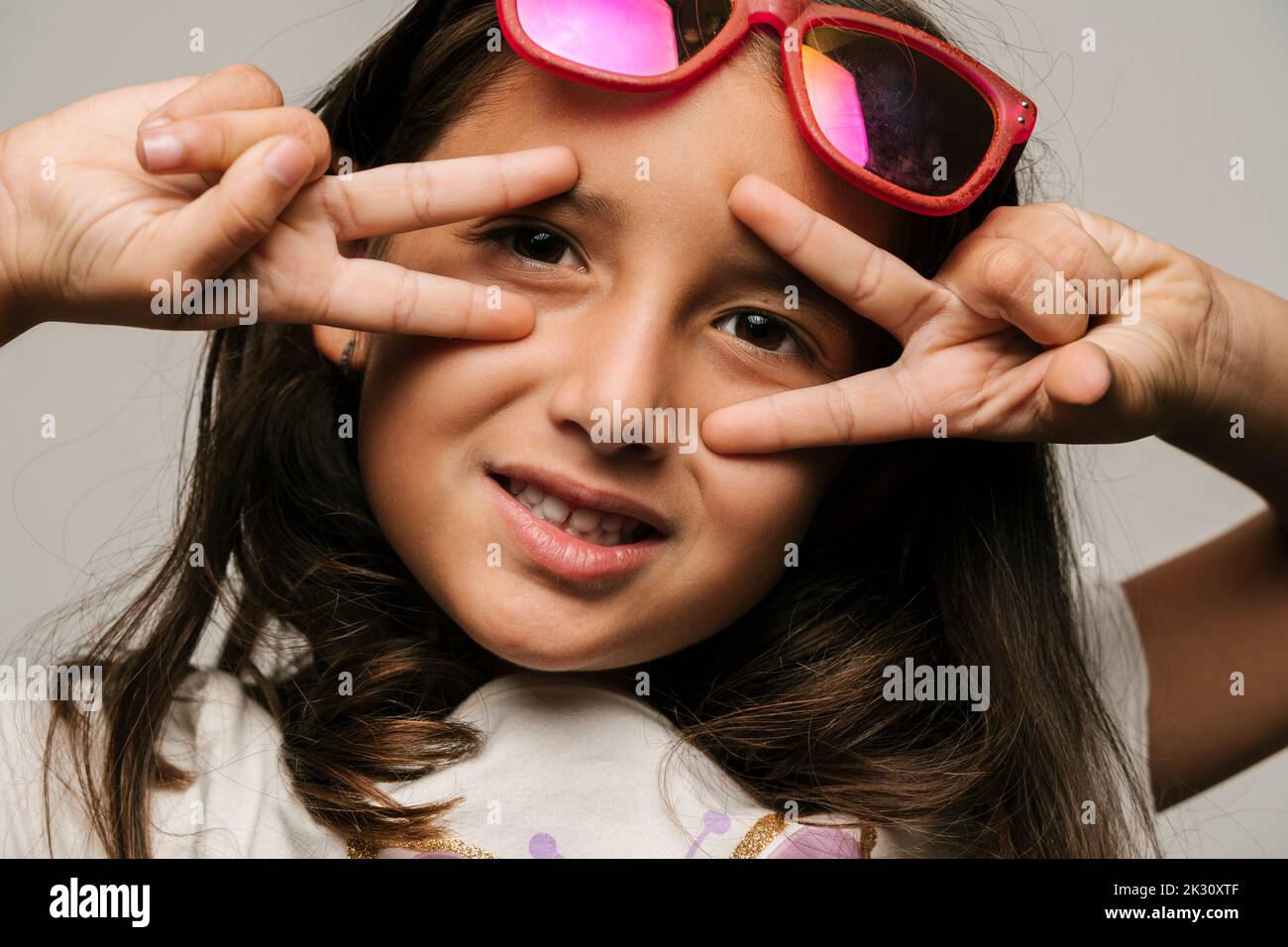 Smiling girl gesturing peace signs Stock Photo - Alamy