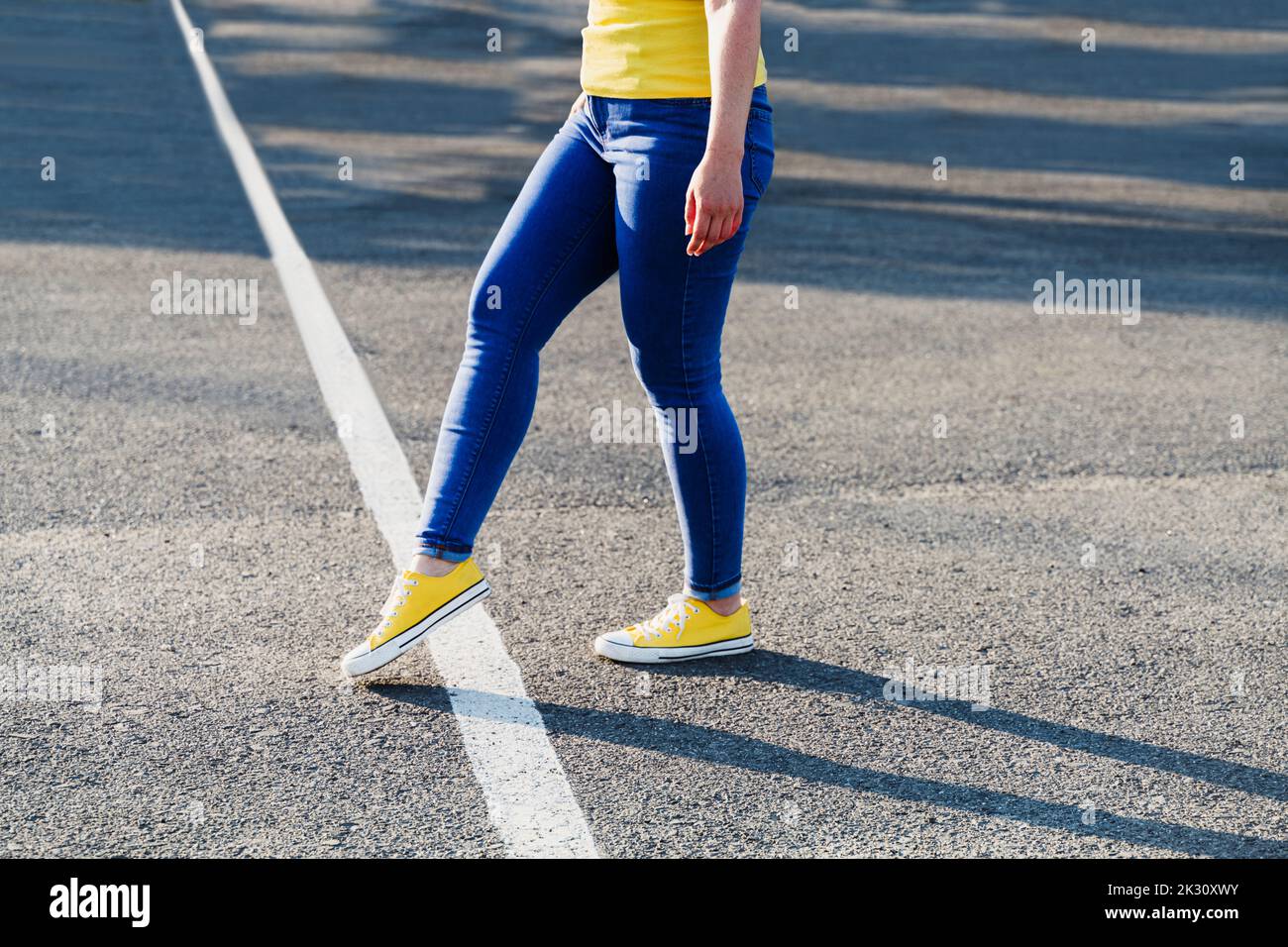 Woman wearing canvas shoes crossing line drawn on road Stock Photo - Alamy