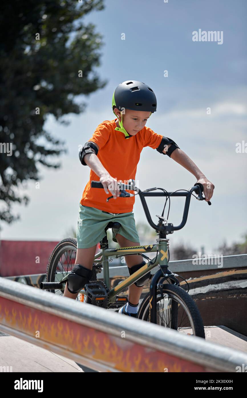 Determined boy wearing helmet riding BMX bike Stock Photo - Alamy