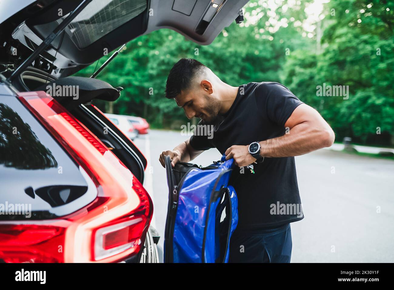 Man looking in backpack standing outside car Stock Photo - Alamy