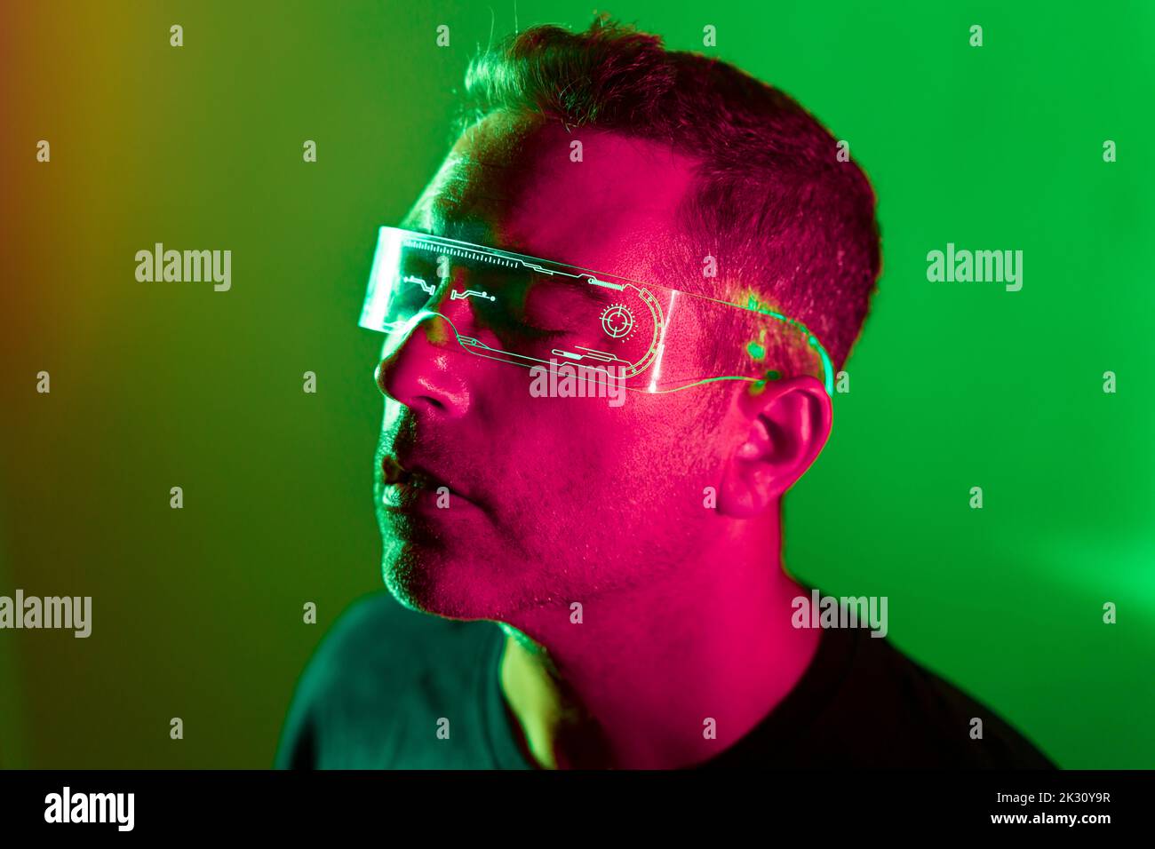 Man with eyes closed wearing smart glasses against green background ...