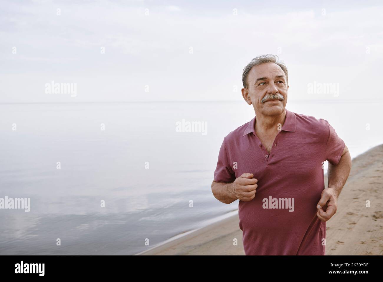 Thoughtful senior man running by sea at beach Stock Photo - Alamy