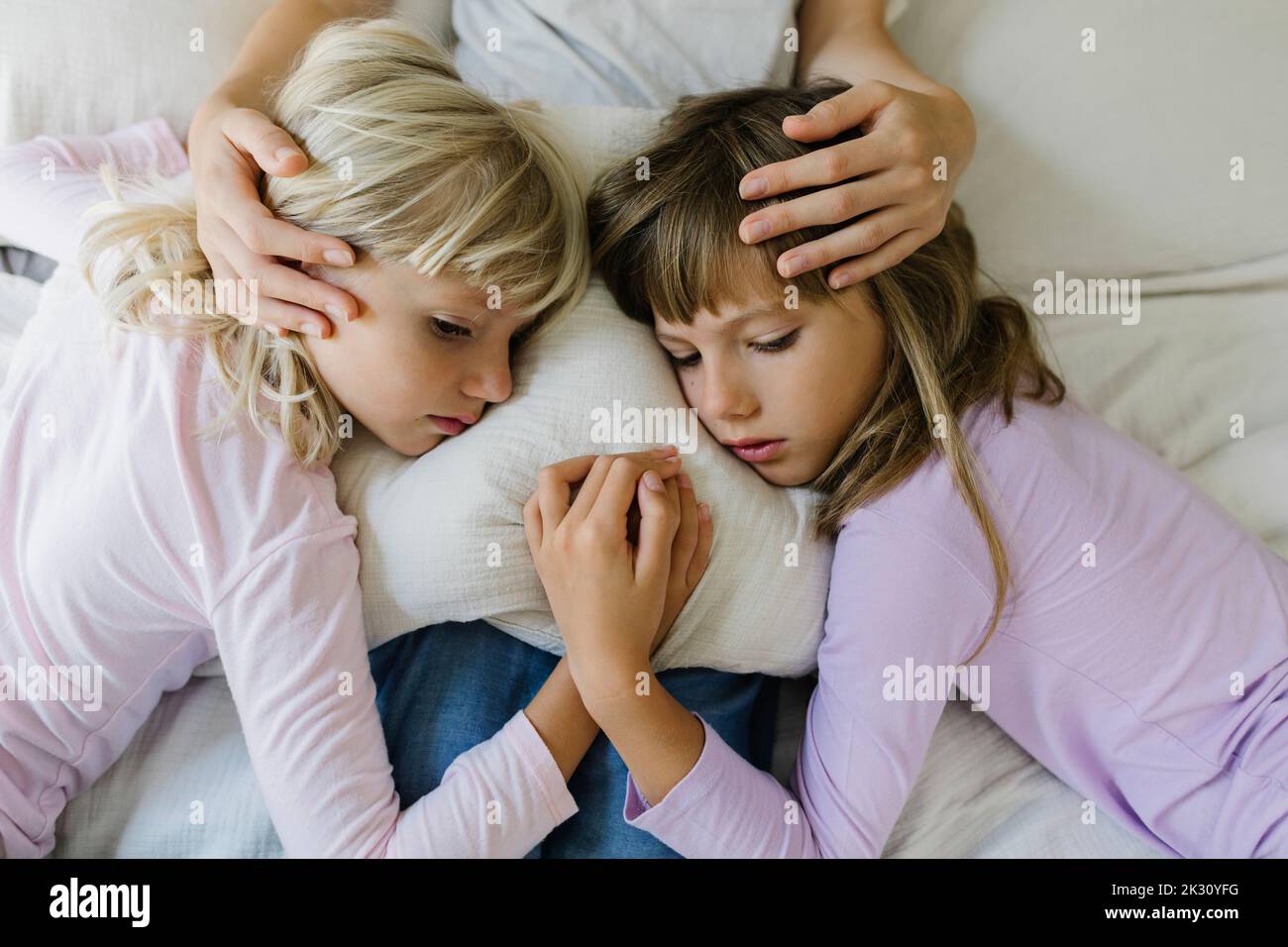 Sad siblings resting over cushion on lap of mother at home Stock Photo ...