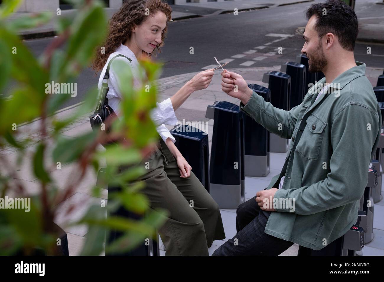 Man and woman playfighting with spoons sitting at bicycle parking ...