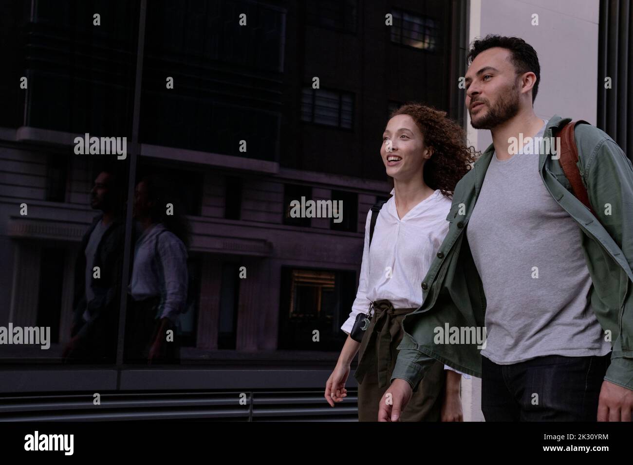 Smiling friends walking and talking by building Stock Photo - Alamy