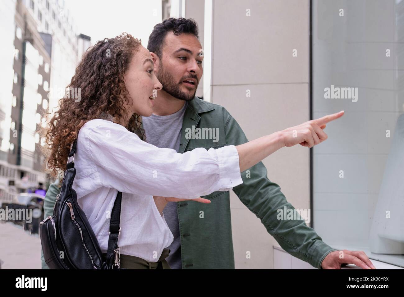 Excited woman pointing at store window standing by man Stock Photo - Alamy