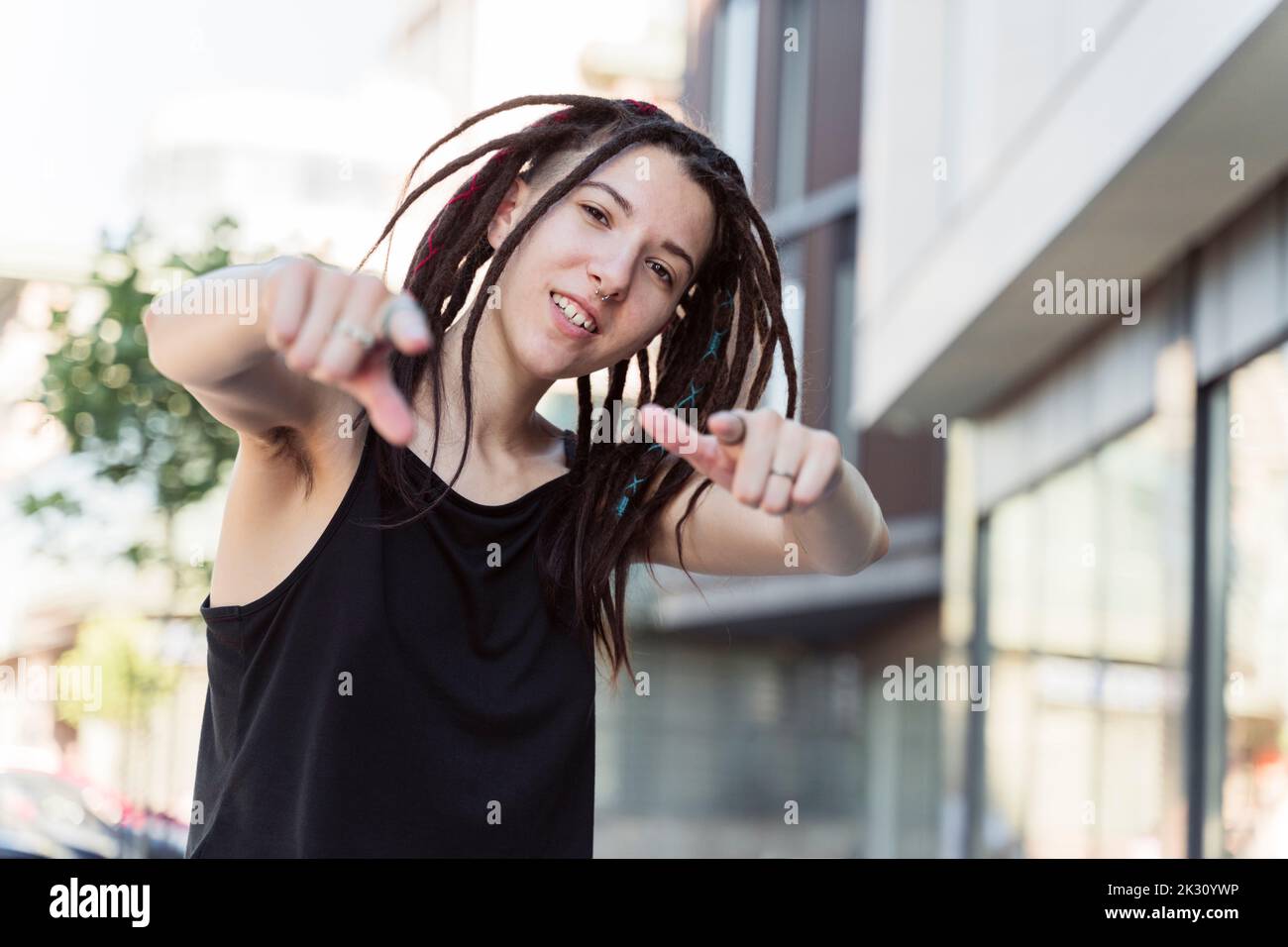 Non-binary hipster with locs hairstyle making hand signs Stock Photo ...