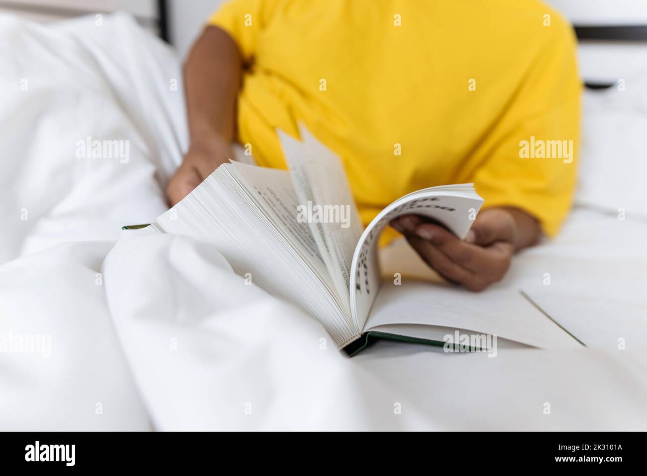 Woman flipping through a book sitting in bed close up Stock Photo - Alamy