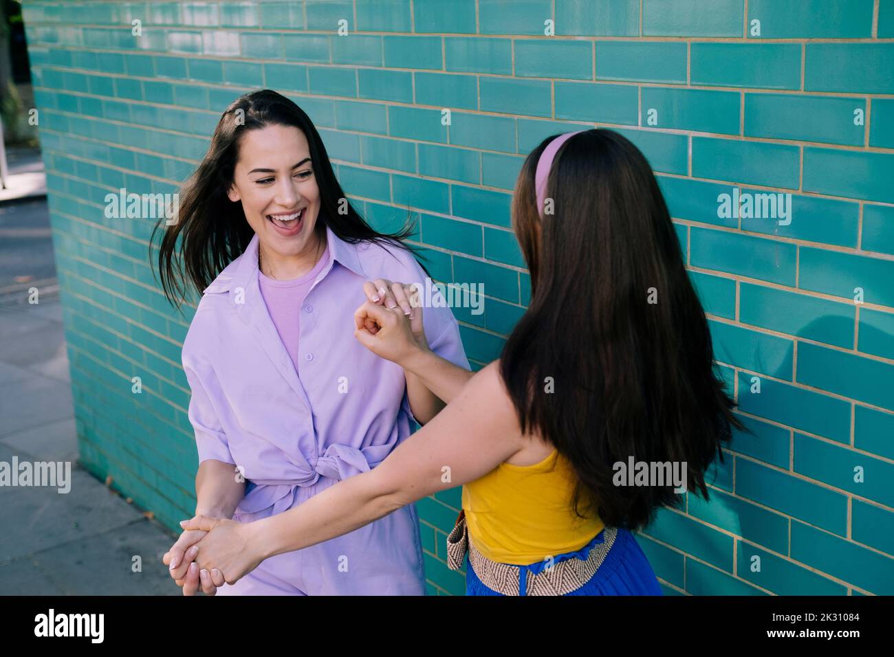 Happy friends dancing with each other near brick wall Stock Photo - Alamy