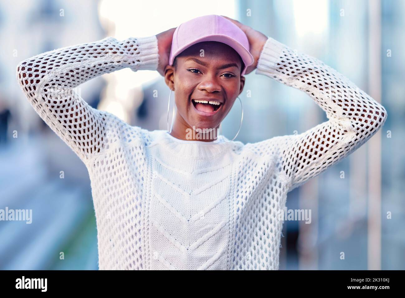 Cheerful woman wearing pink cap with hands behind head Stock Photo - Alamy