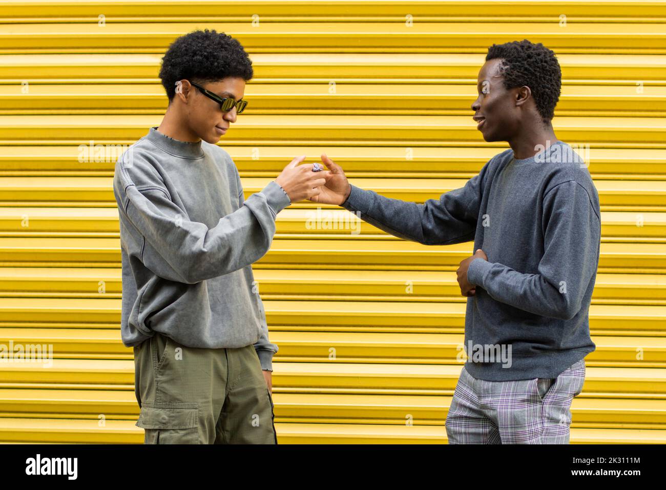 Friends greeting each other in front of yellow shutter Stock Photo - Alamy