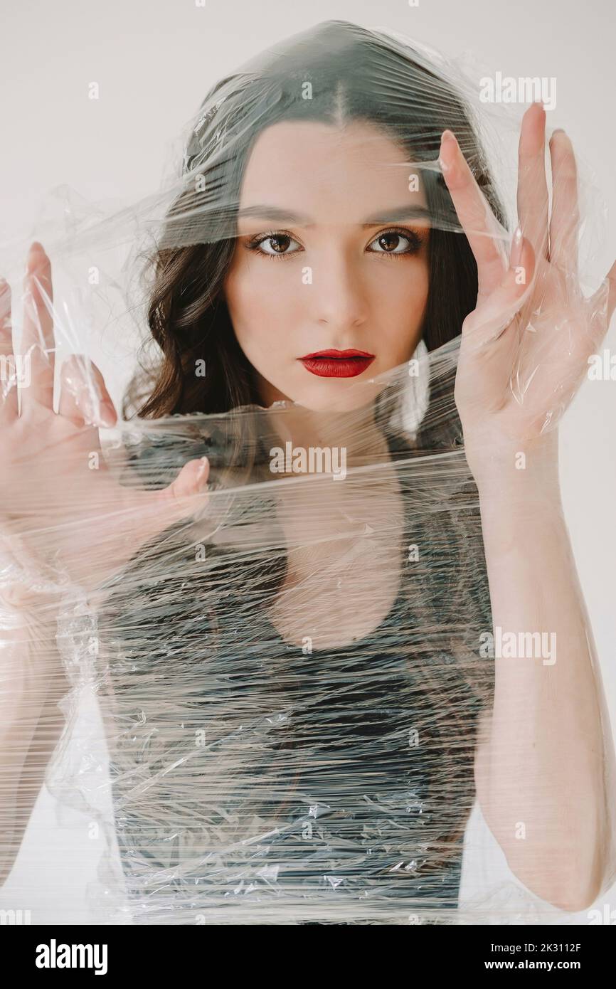 Trapped young woman tearing hole in plastic Stock Photo - Alamy