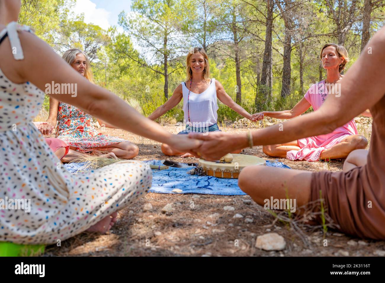 Happy woman with friends holding hands and practicing meditation ...