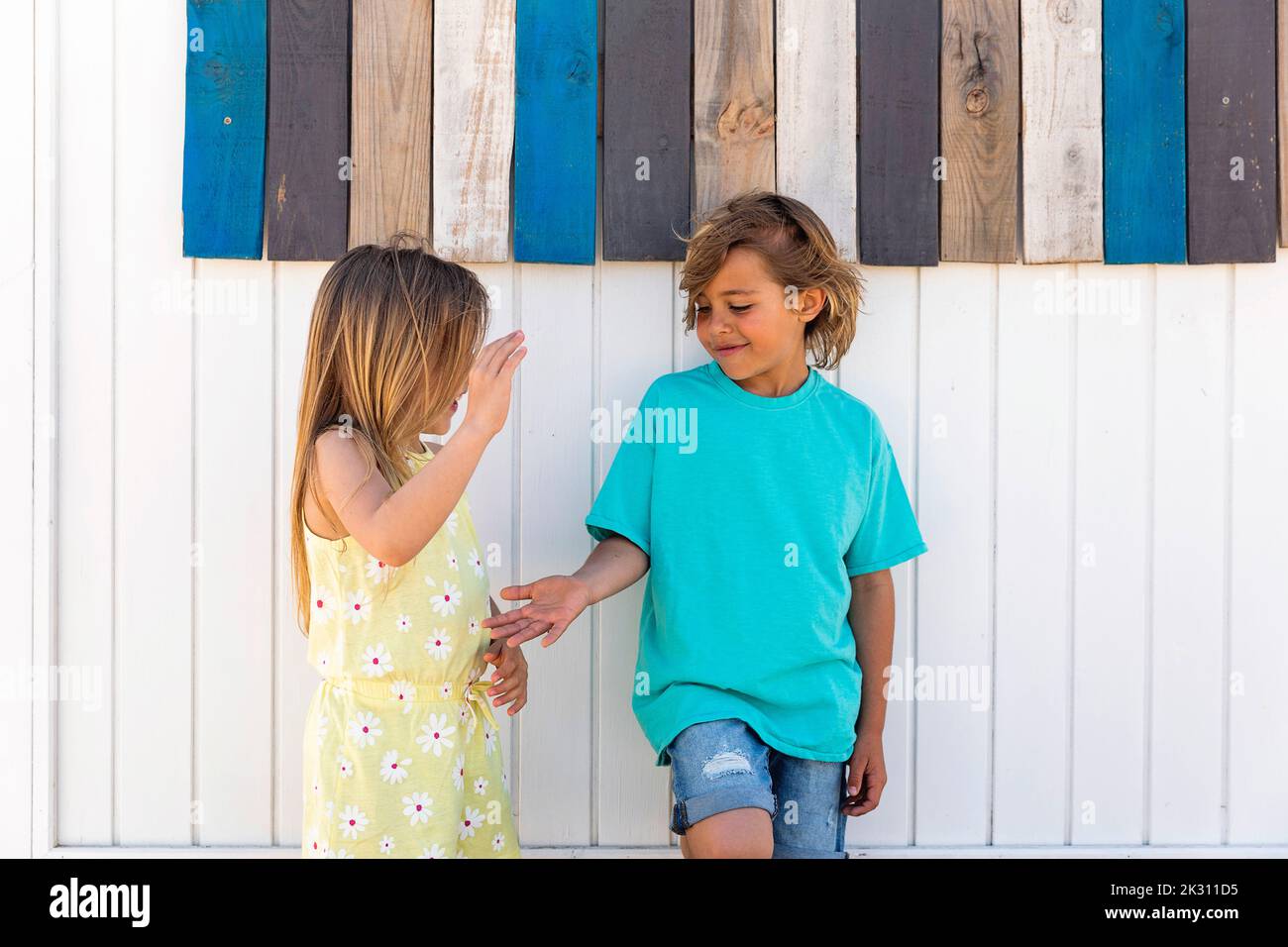 Girl playing clapping game with brother in front of wooden wall Stock ...