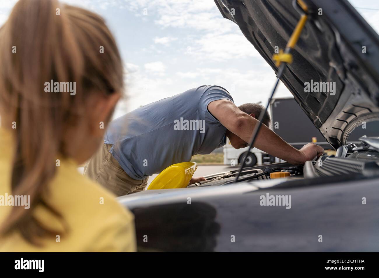Mature man repairing car in front of girl at parking lot Stock Photo ...