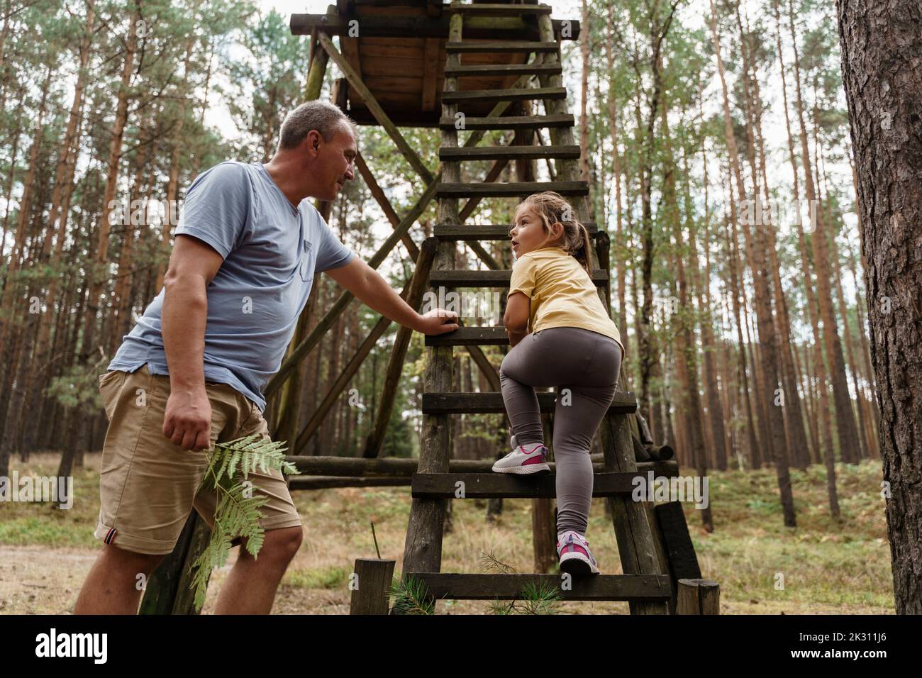 Mature man helping girl to climb ladder of hunting blind Stock Photo ...