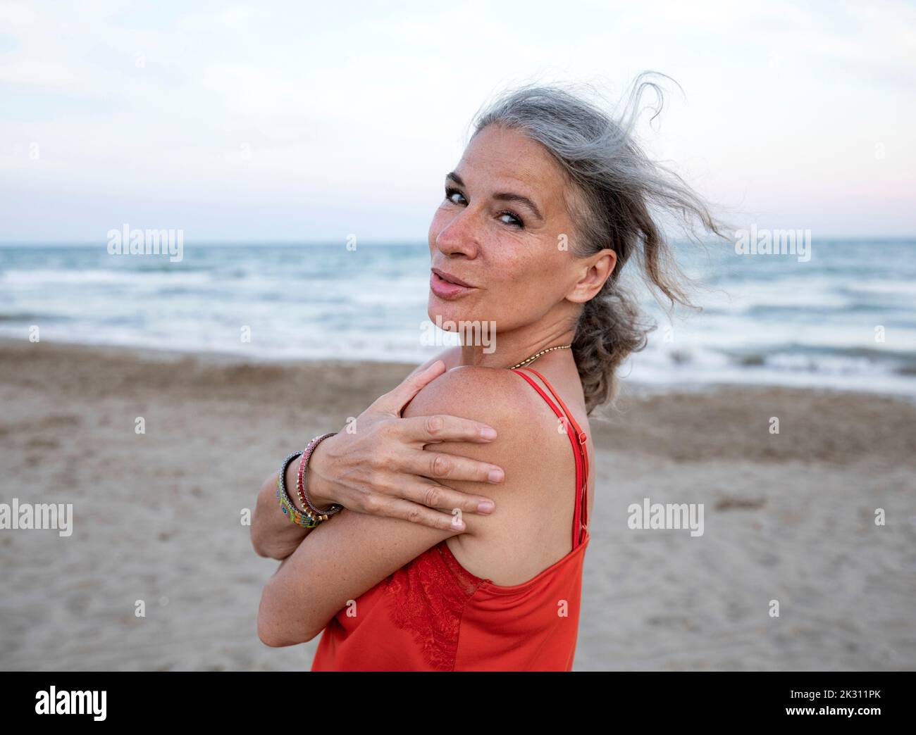 Senior woman hugging self at beach Stock Photo - Alamy