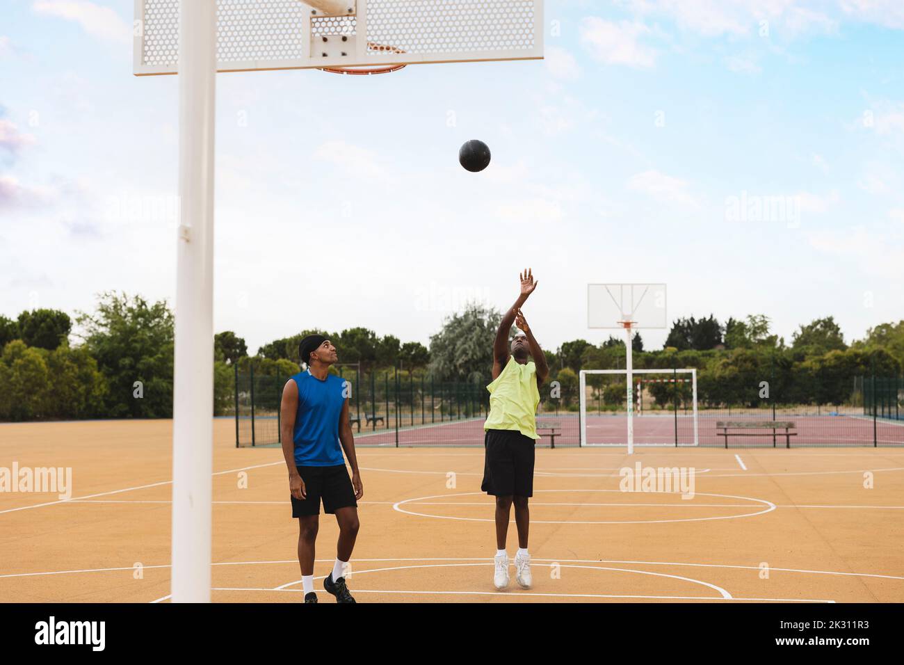 Young man looking at father shooting basketball in hoop Stock Photo - Alamy