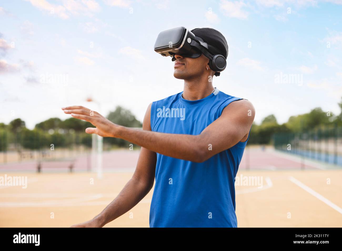 Young man wearing VR glasses gesturing standing at basketball court ...