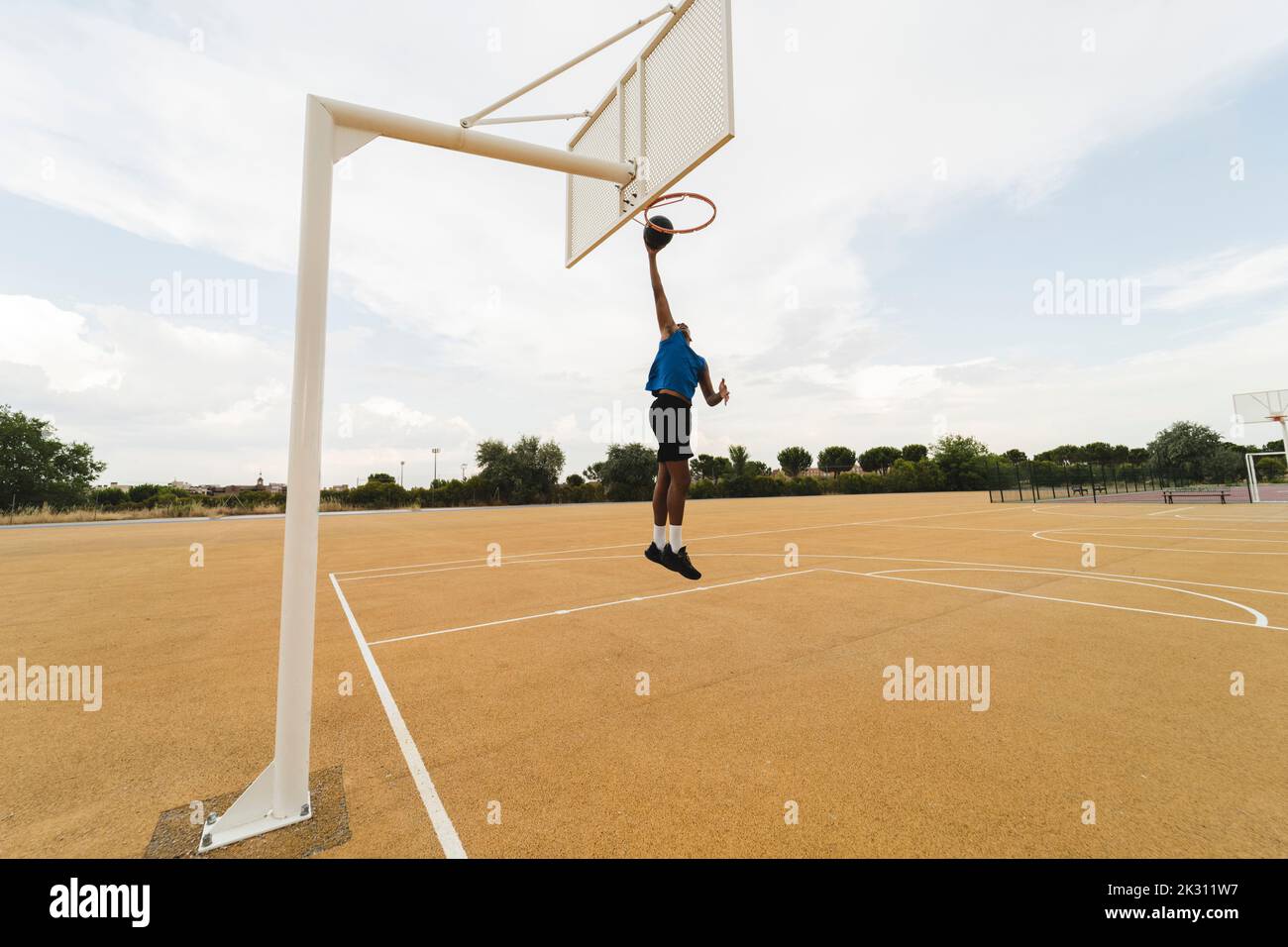 Young man dunking basketball in hoop at sports court Stock Photo - Alamy