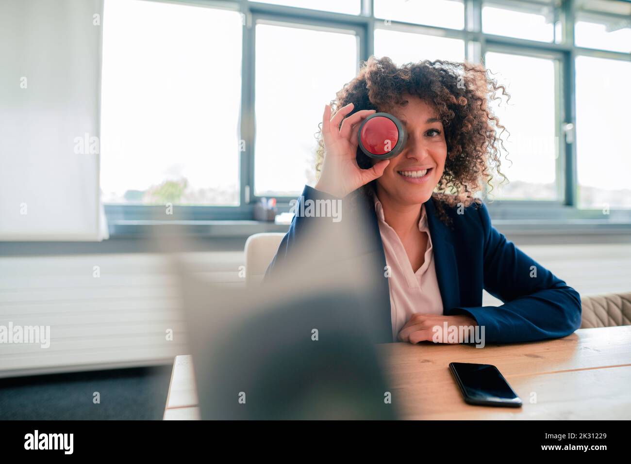 Businesswoman with buzzer button covering eye at office Stock Photo - Alamy