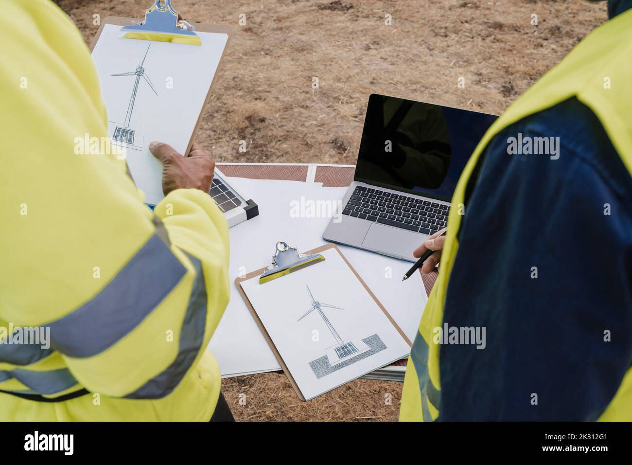 Engineer with clipboard by colleague at desk at wind farm Stock Photo ...