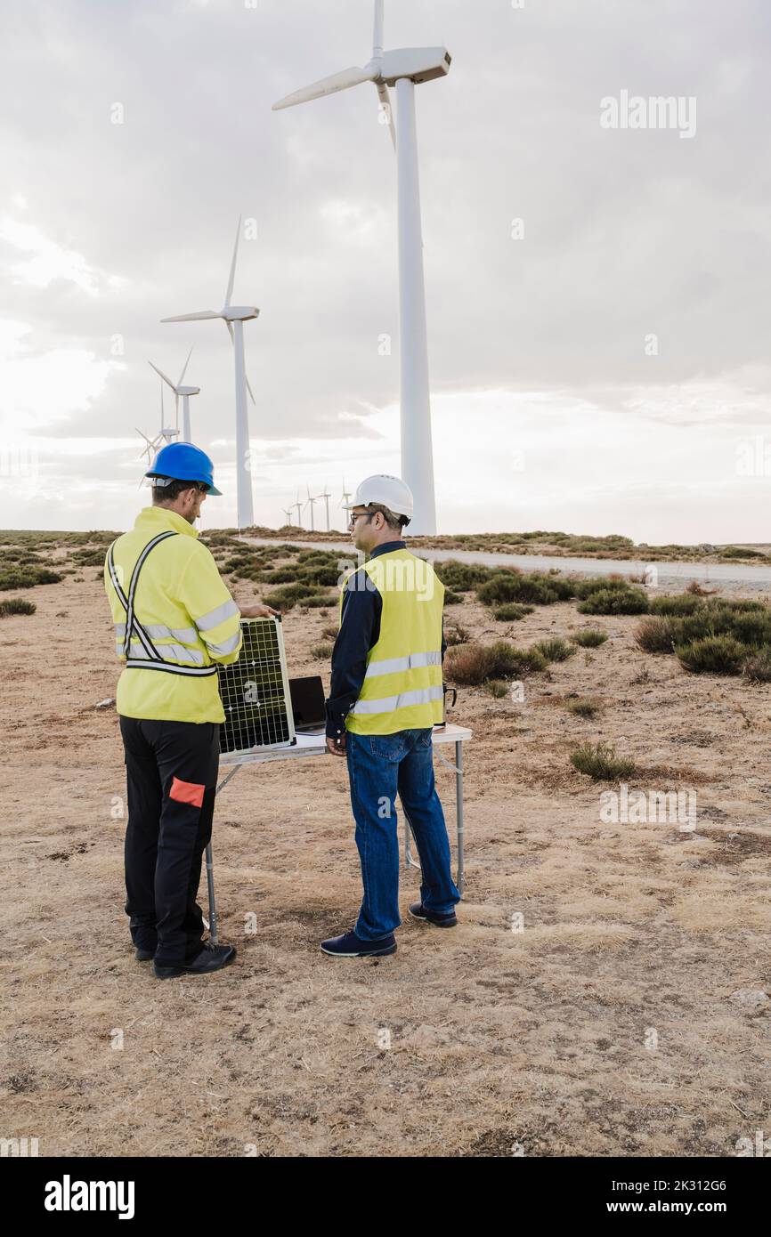 Engineers talking to each other standing at wind farm Stock Photo - Alamy