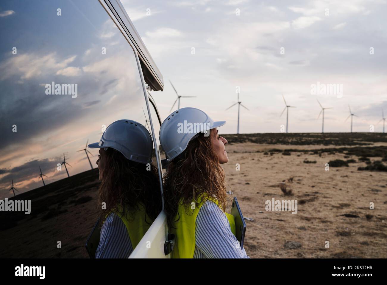 Engineer wearing hardhat leaning on van at wind farm Stock Photo - Alamy
