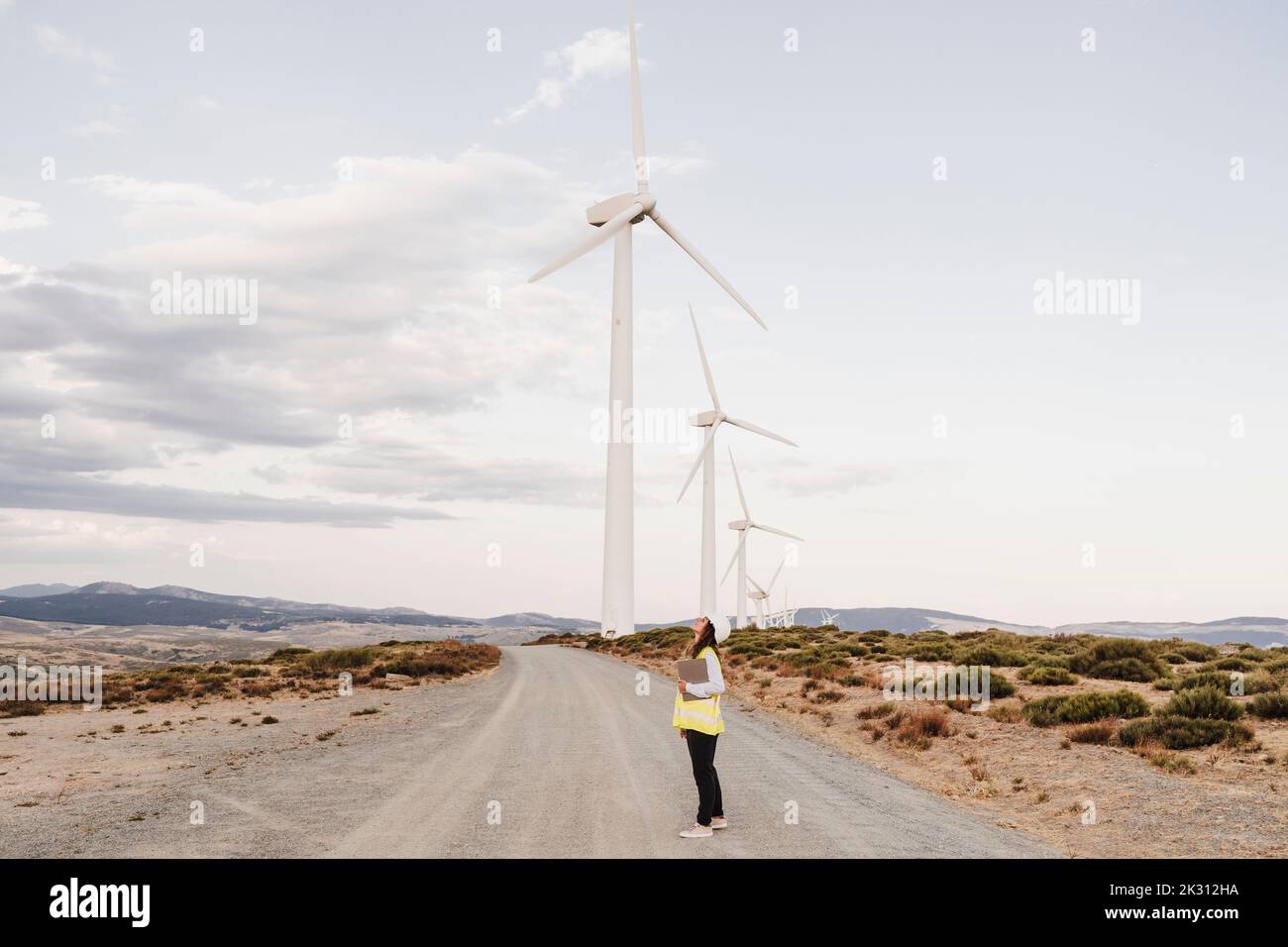 Engineer standing on dirt road by wind turbines at wind farm Stock ...