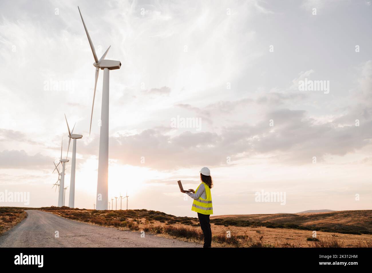 Engineer looking at wind turbines at wind farm on sunset Stock Photo ...