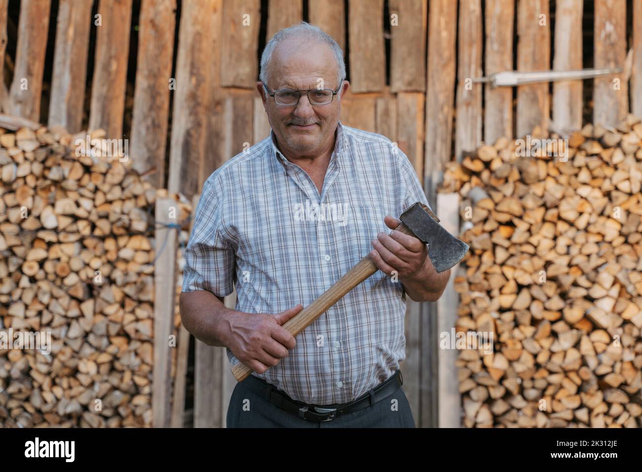 Senior man holding axe standing at back yard Stock Photo - Alamy