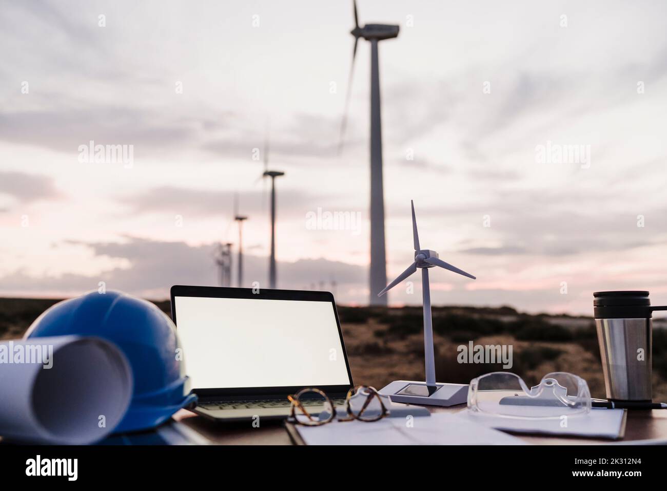 Wind turbine model by laptop with blank screen on desk at wind farm ...