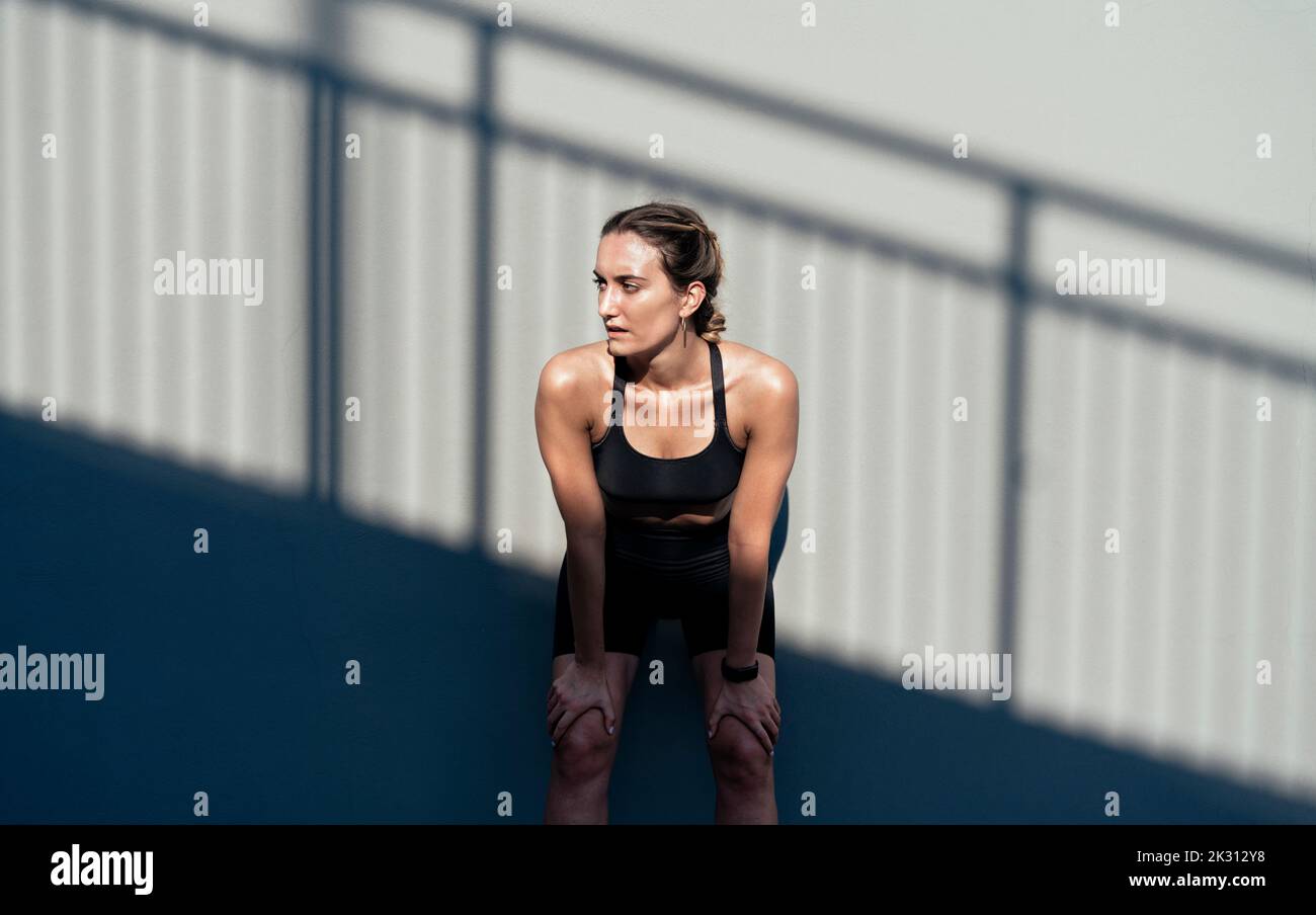 Tired young woman relaxing standing in front of wall Stock Photo - Alamy
