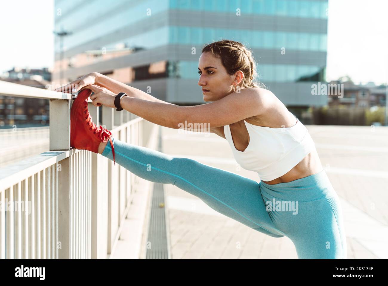 Young woman stretching leg on railing Stock Photo - Alamy