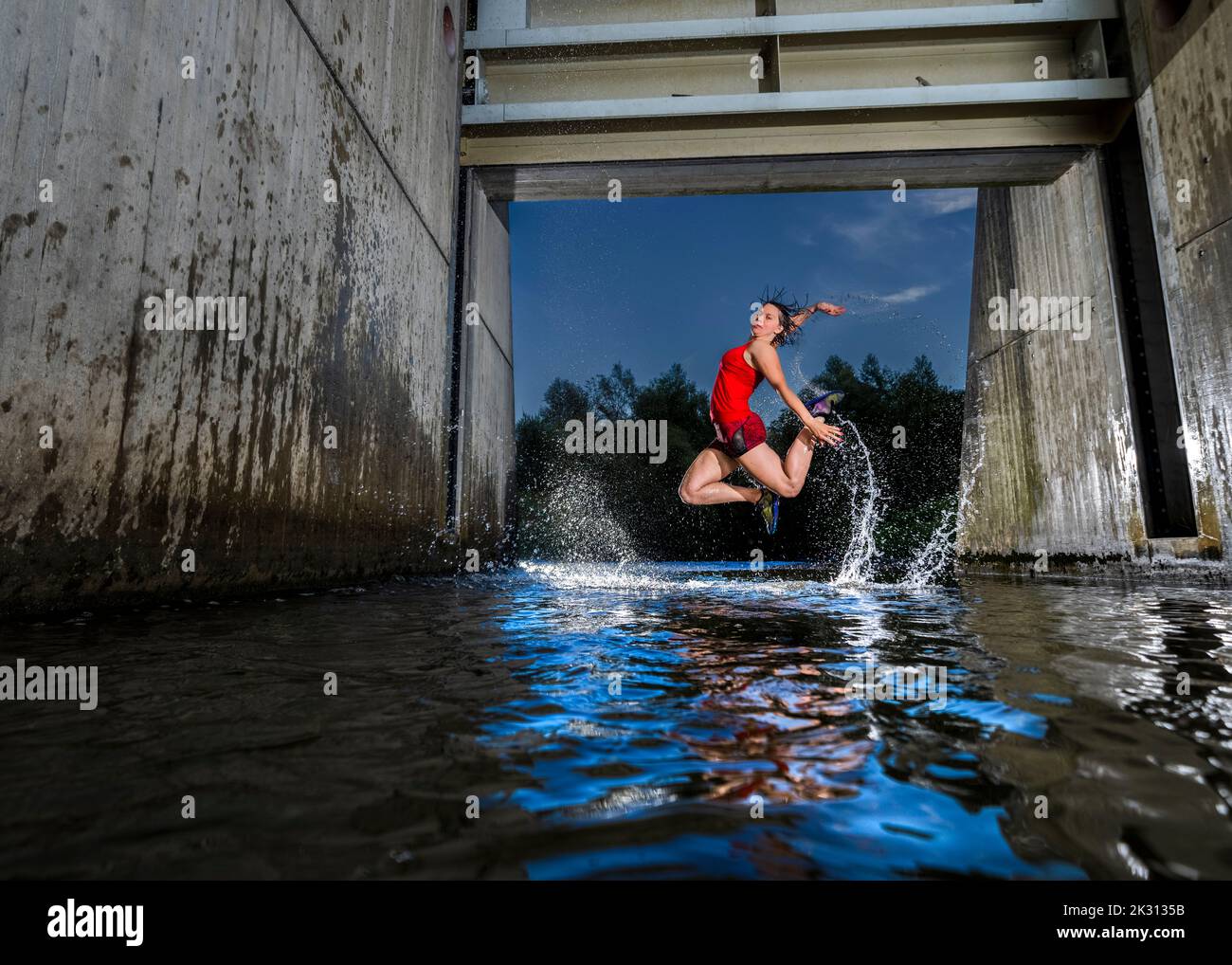 Active young woman jumping over water at dusk Stock Photo - Alamy