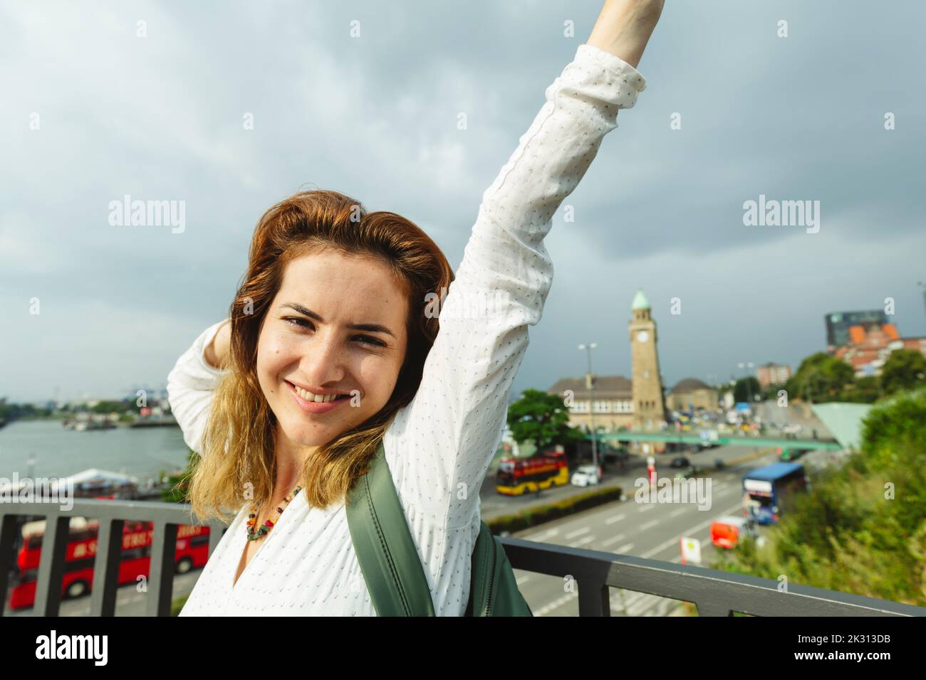 Happy woman with arm raised standing by railing, Hamburg, Germany Stock ...