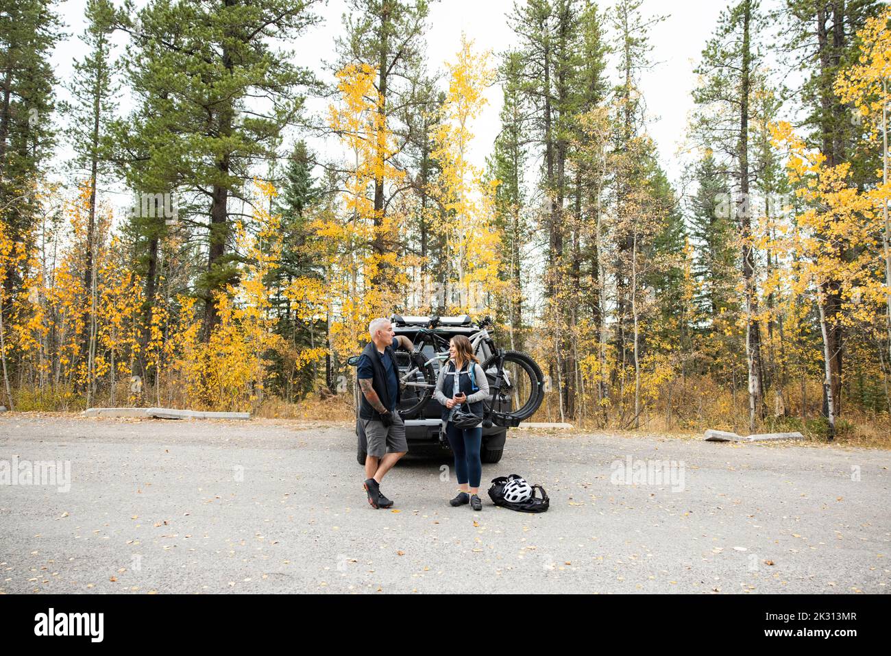 Couple standing next to SUV with bike rack in forest Stock Photo - Alamy