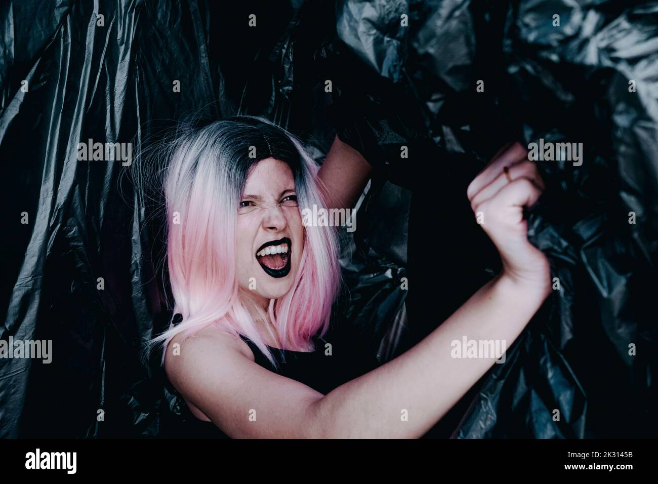 Angry woman screaming and tearing black plastic Stock Photo - Alamy