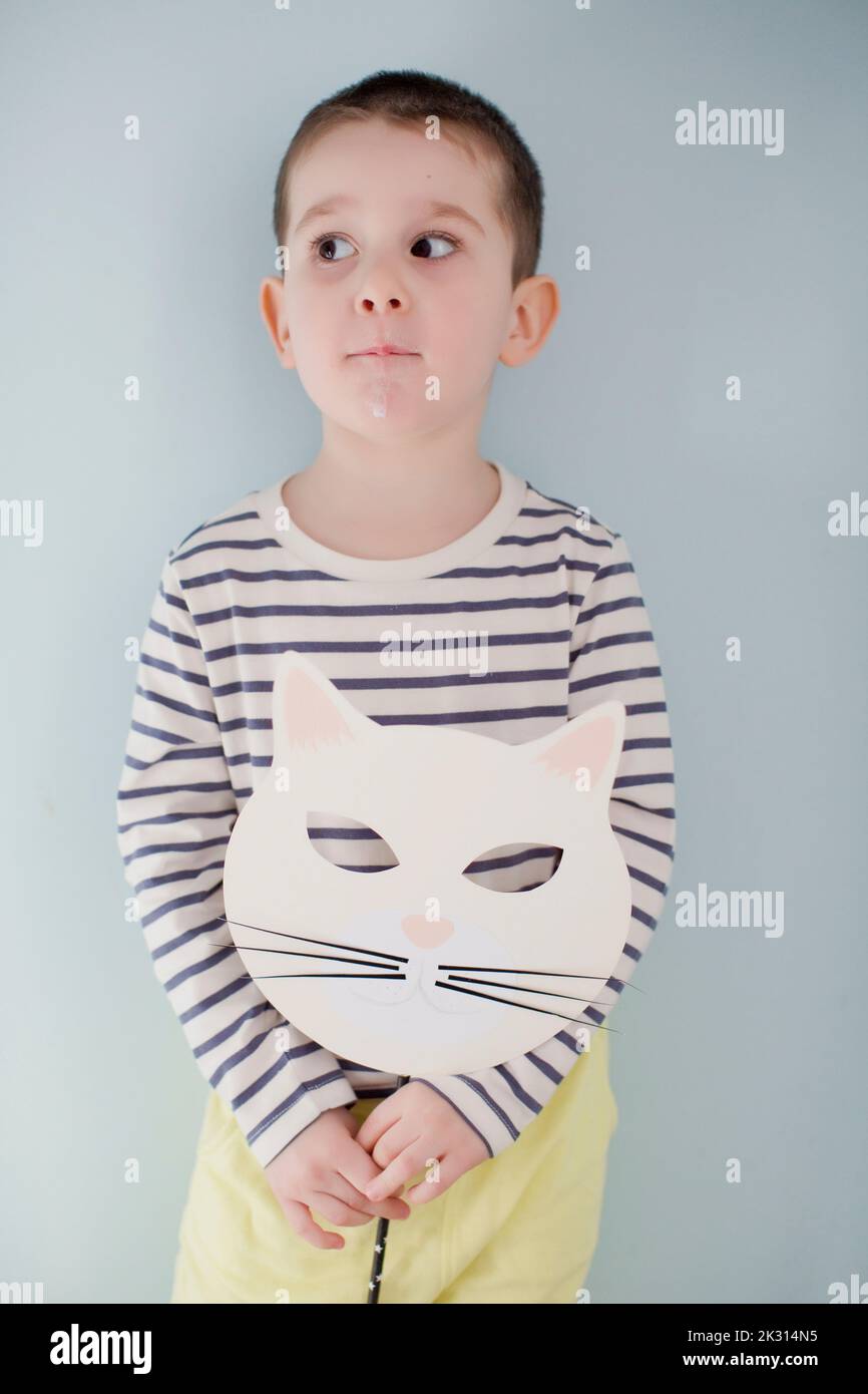 Innocent boy standing with Halloween mask in front of gray mask Stock ...