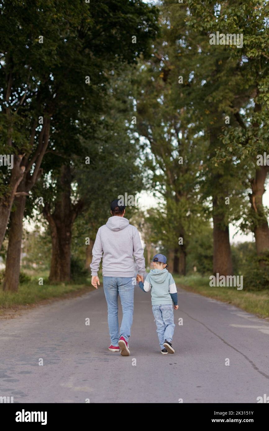Man holding son's hand walking on footpath Stock Photo - Alamy